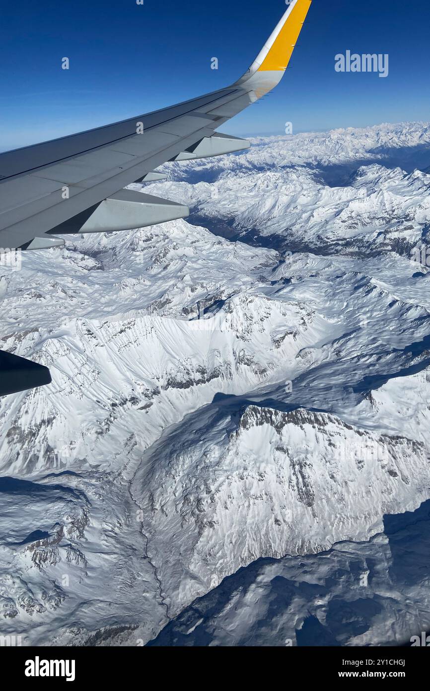 Airplane flying low over snowy mountains and preparing for landing to ...