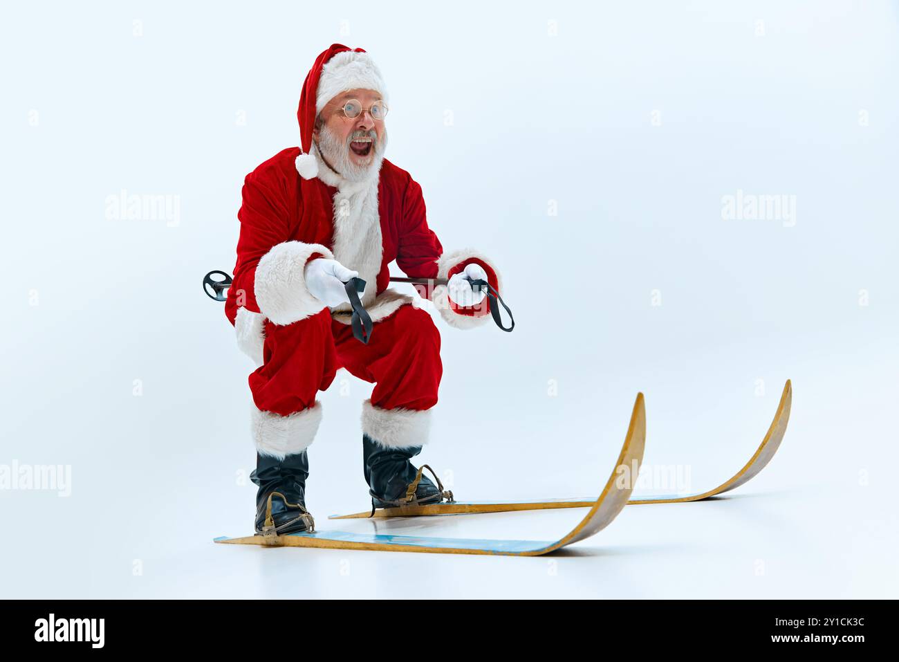Santa Claus crouching on skis, gripping poles, wearing full costume ...