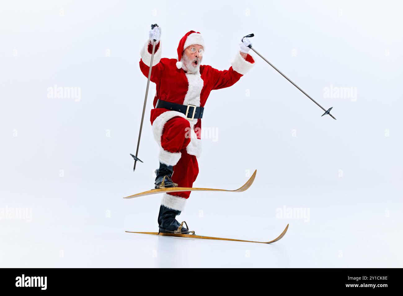 Santa Claus skiing with large red cape behind him, holding ski poles ...