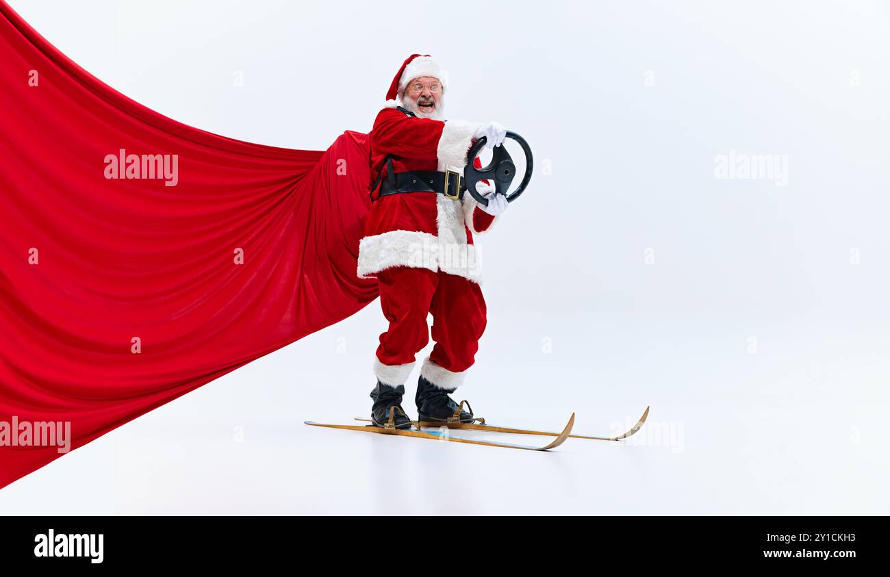 Santa Claus skiing with arms raised, holding ski poles, red cape ...