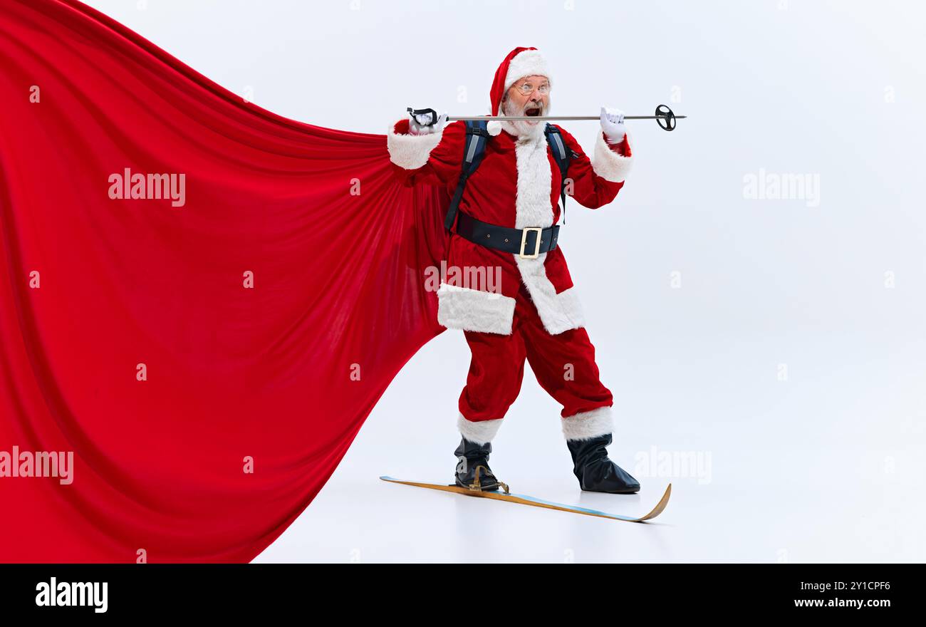 Santa Claus skiing with red cape, holding ski pole horizontally in arms ...