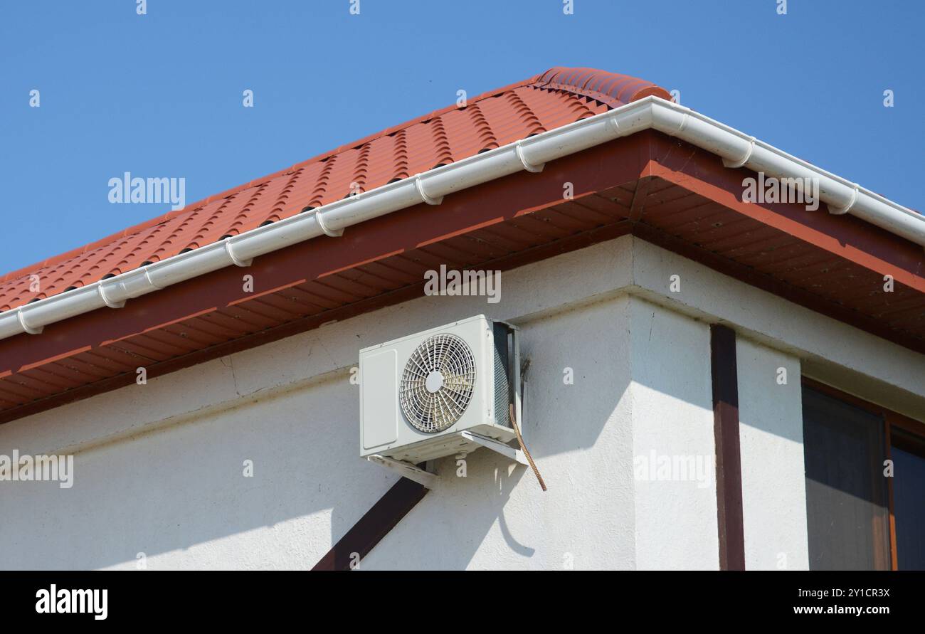 An air conditioner is installed on the house with a metal red roof ...