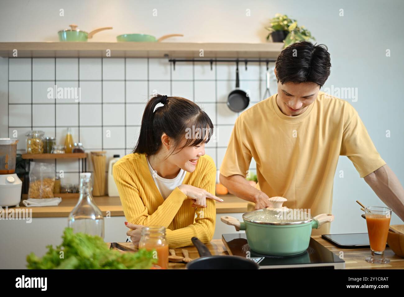 Beautiful young couple cooking together in a modern kitchen and ...