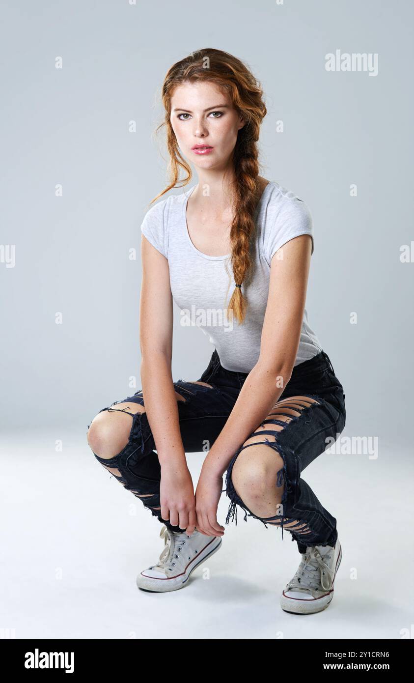 Portrait, fashion and cool woman in studio to relax in ripped jeans ...