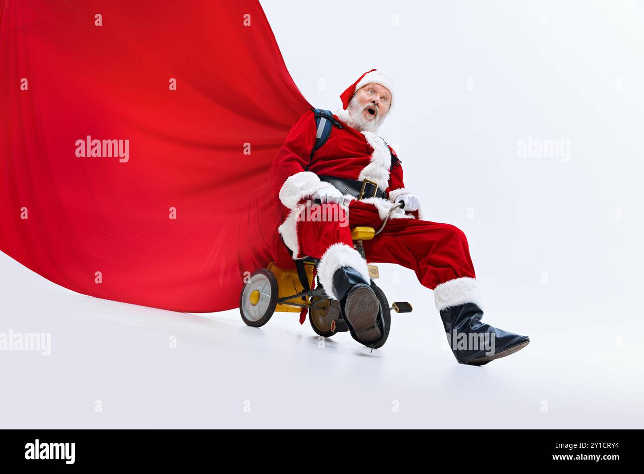 Santa Claus with white beard riding tricycle carrying huge red bag of ...