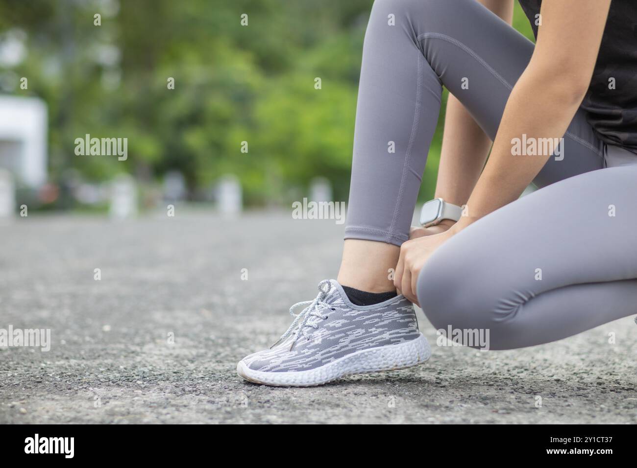 Young Asian woman in sports bra is putting on her shoes and checking ...
