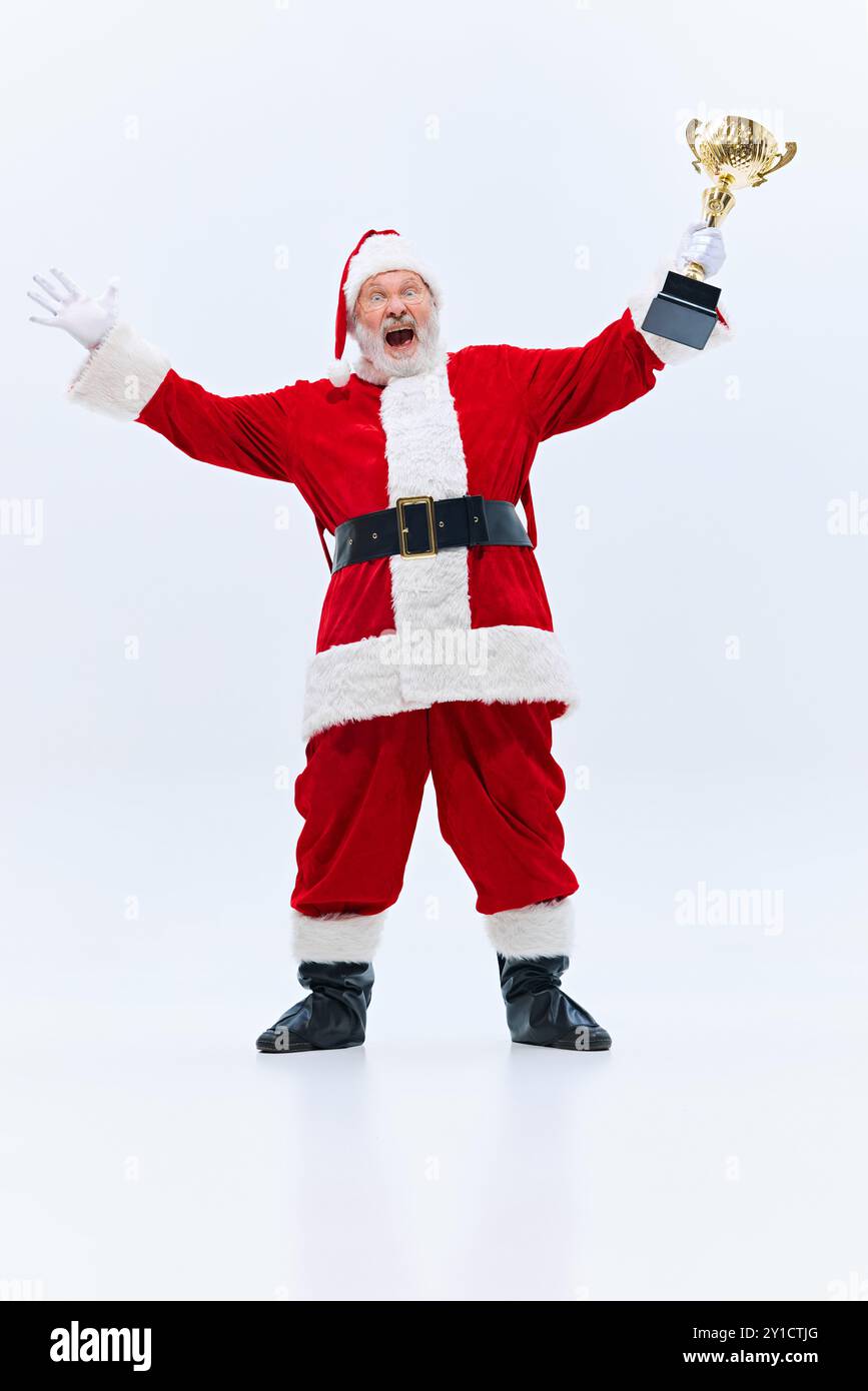 Santa raises golden trophy triumphantly, arms outstretched, his face ...