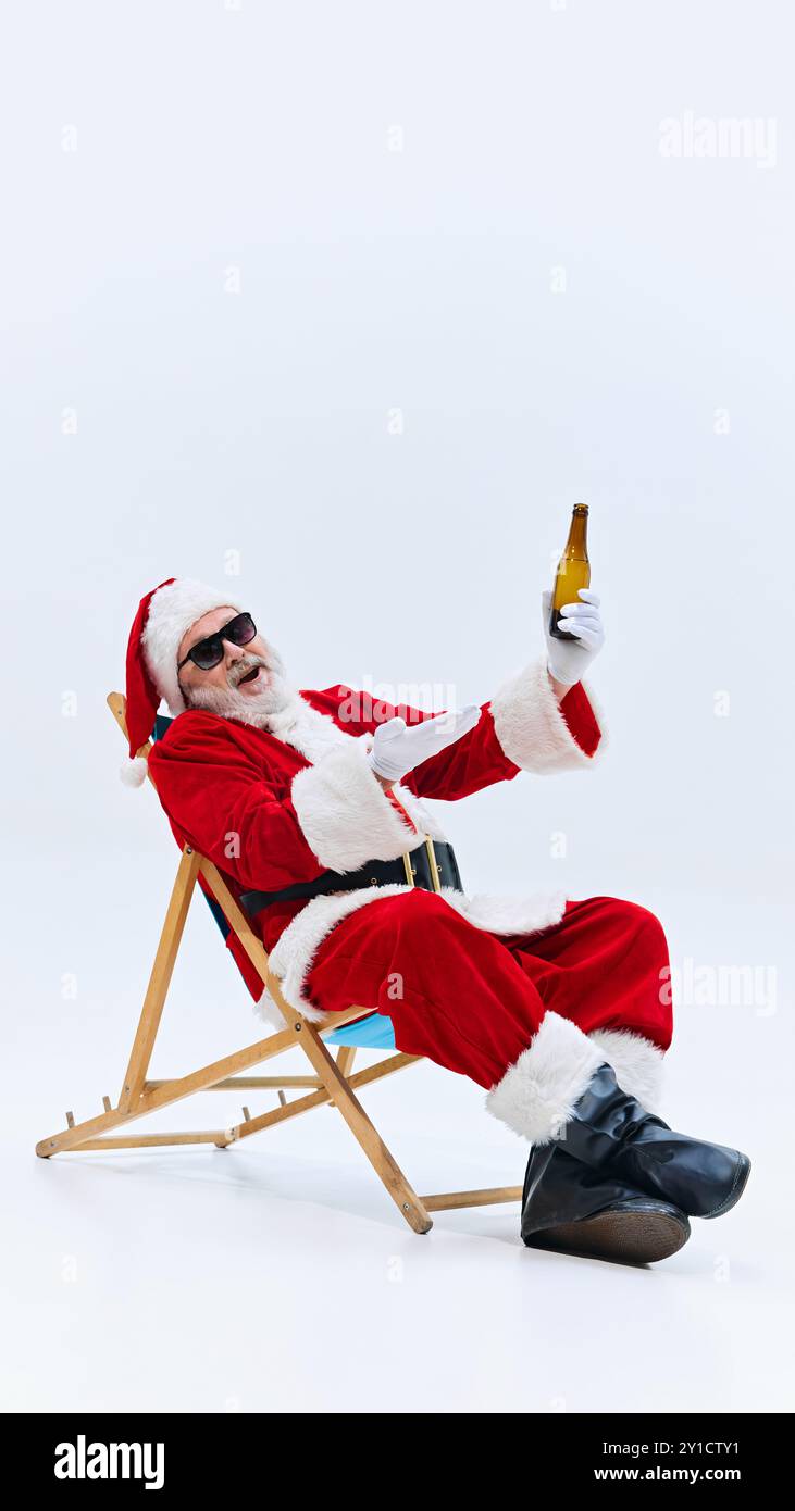 Santa leans back in chair, enjoying beer in his hand, wearing ...
