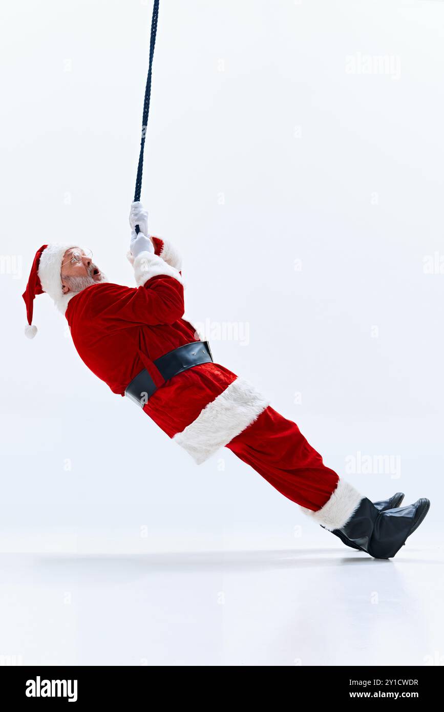 Santa Claus hanging onto blue rope, looking surprised against white ...
