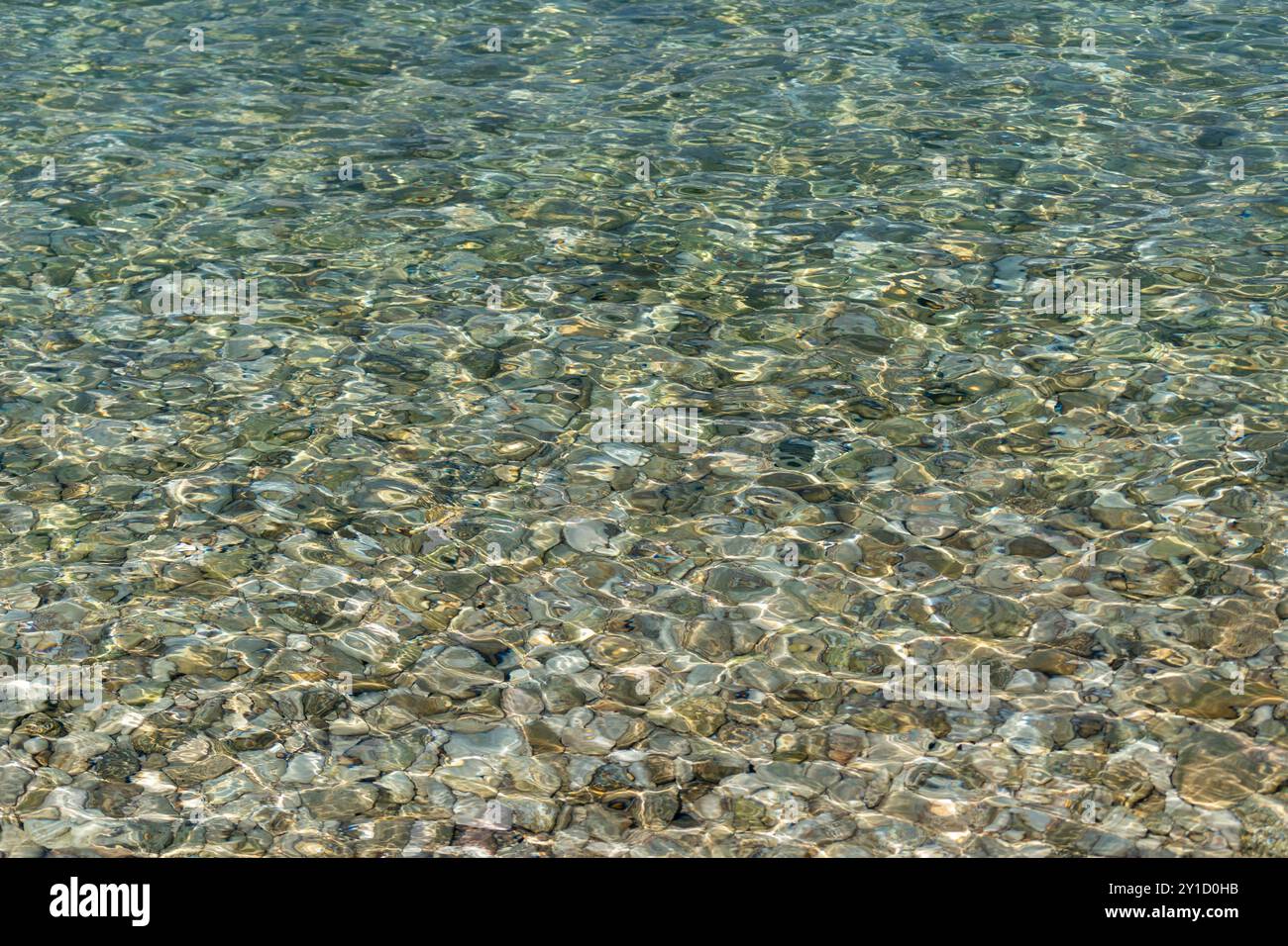 Rippling sea water surface, clear shallow water and stones at bottom ...