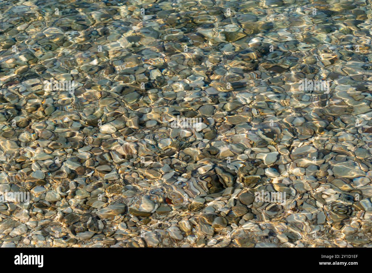 Rippling sea water surface, clear shallow water and stones at bottom ...