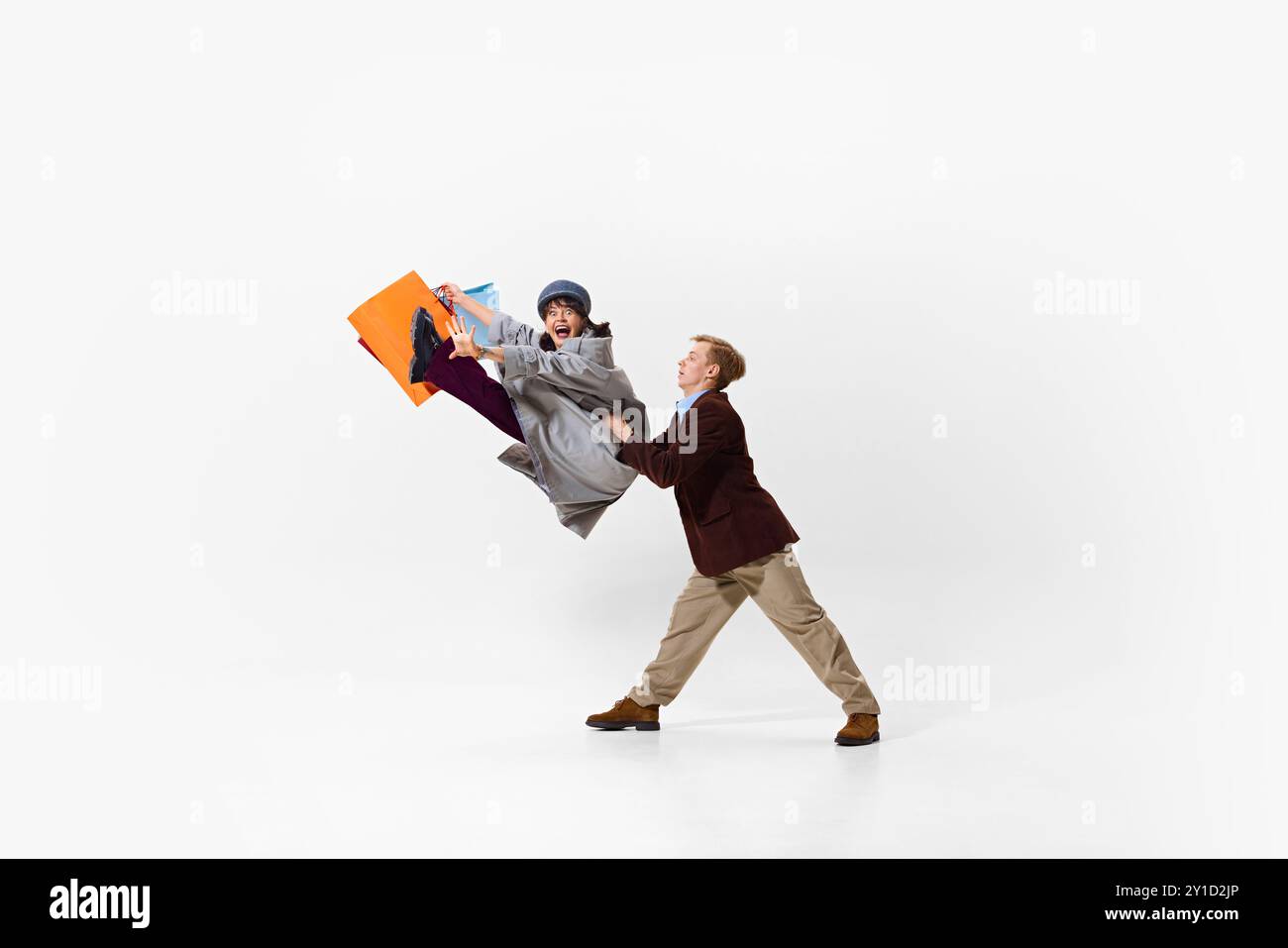 Emotional young woman with many shopping bags cheerfully jumping to man ...