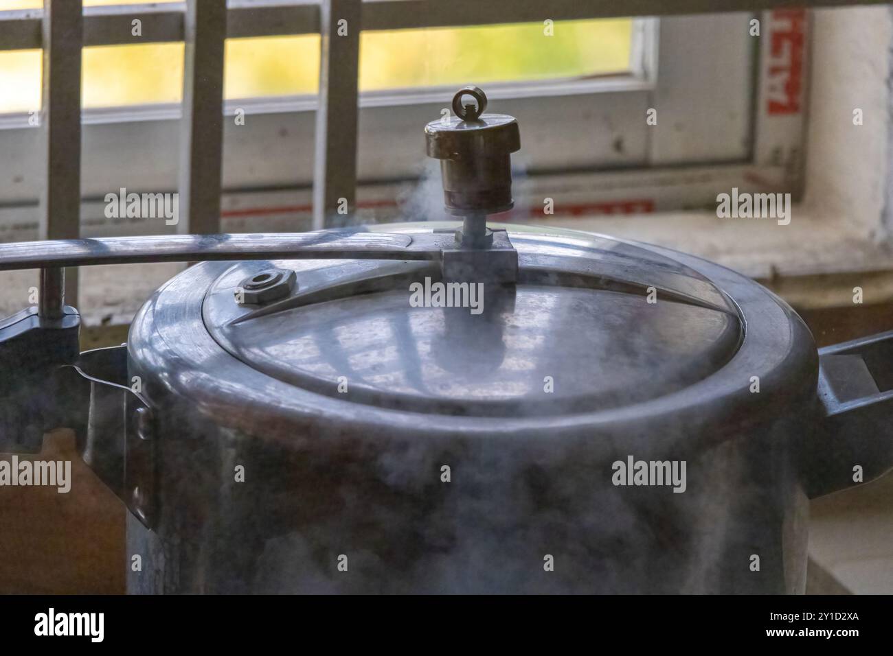 Steam escaping from the pressure cooker's lid with the kitchen's ...