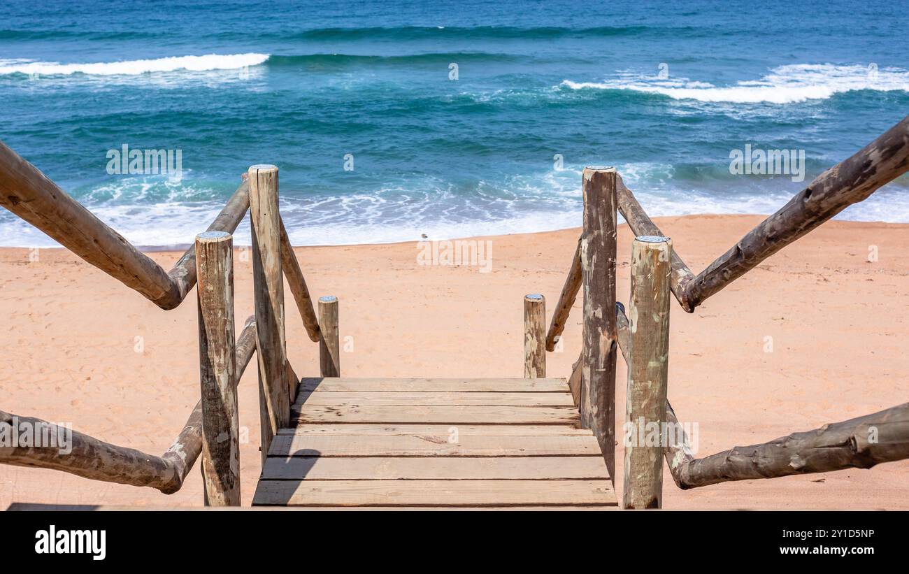 Scenic view wood steps staircase onto beach with blue ocean sea water ...