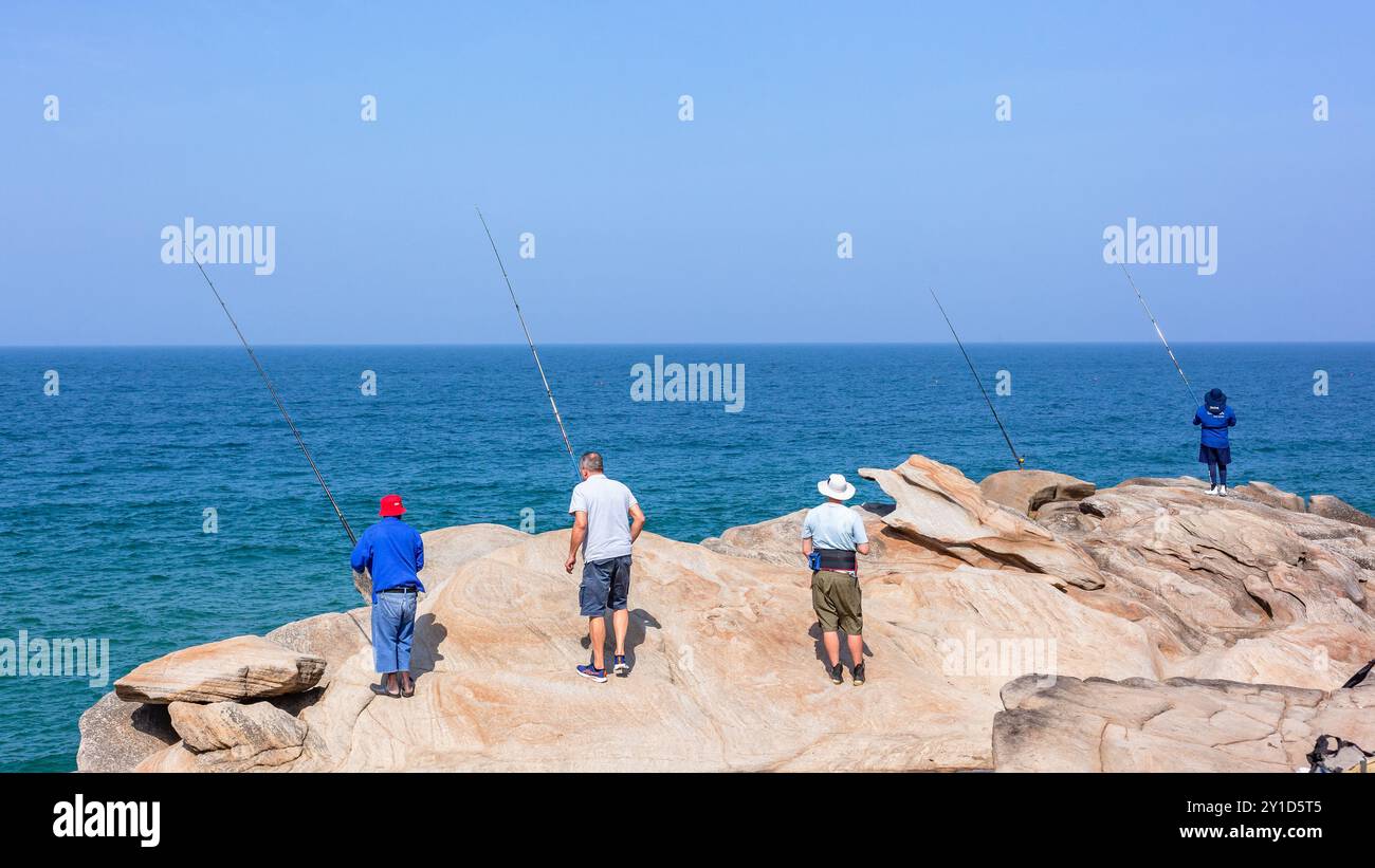 Four fishermen unrecognizable persons fishing off rocks overlooking ...