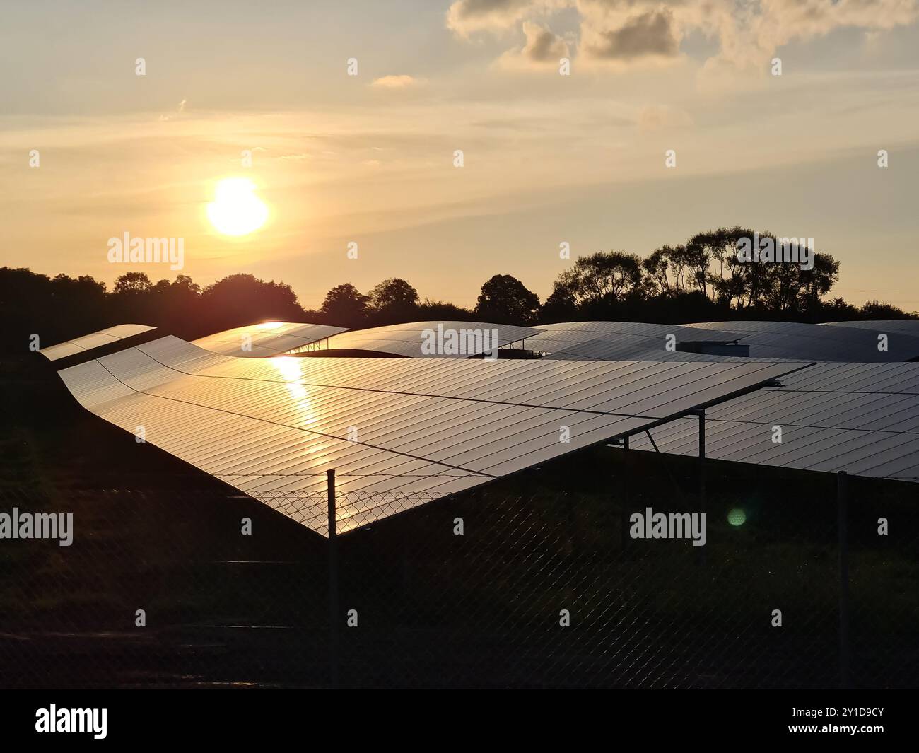 Dark silhouette of a solar park for power generation with the light of ...