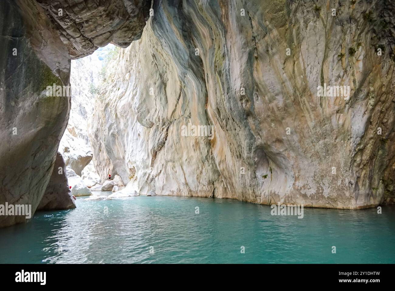 A large cave with a blue river running through it. The cave is very ...