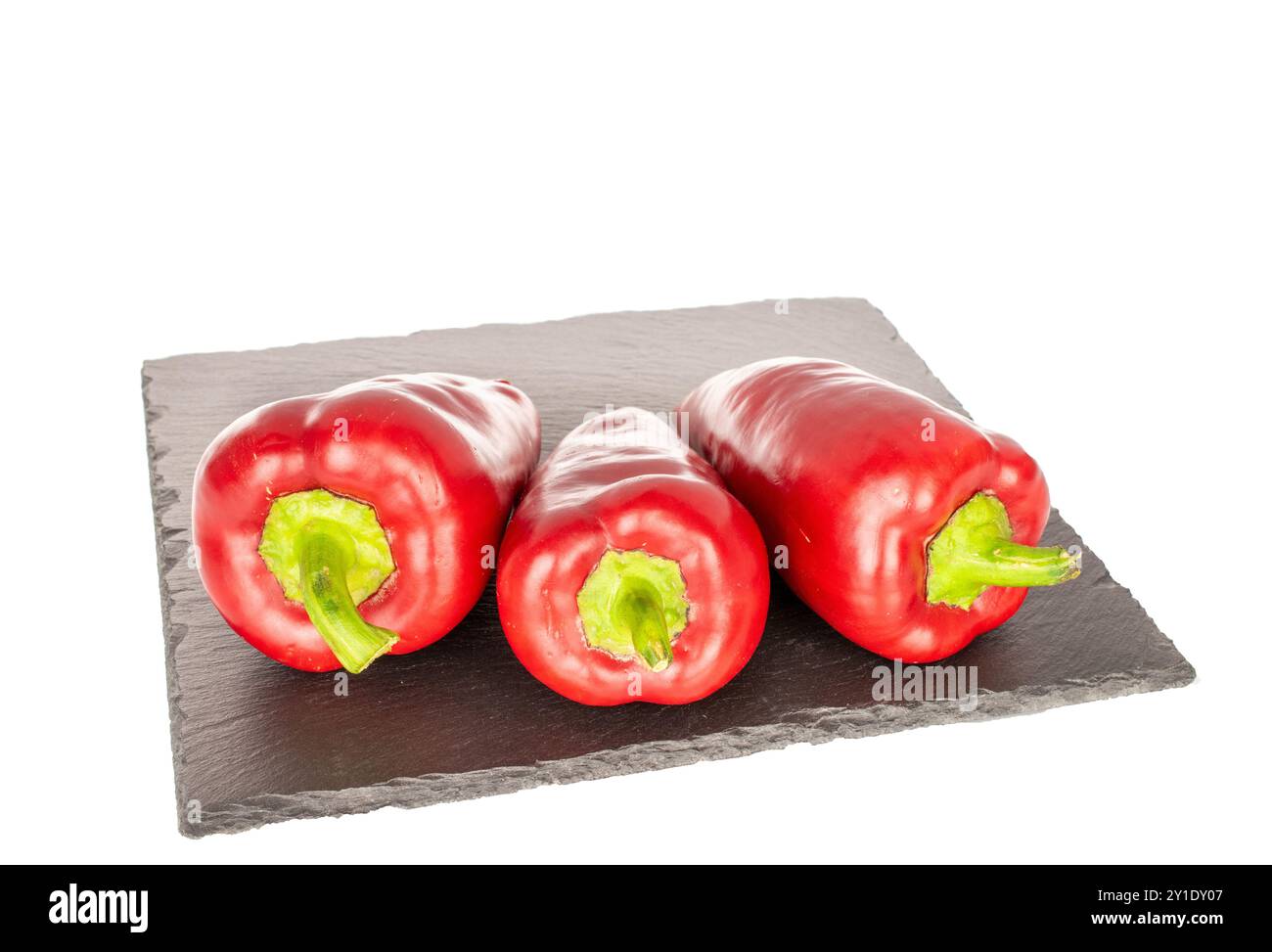 Three sweet red peppers on slate stone, macro, isolated on white ...
