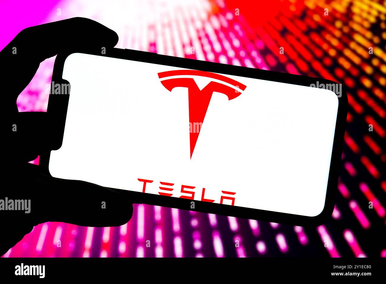 In this photo illustration, a Tesla logo is displayed on the screen of ...