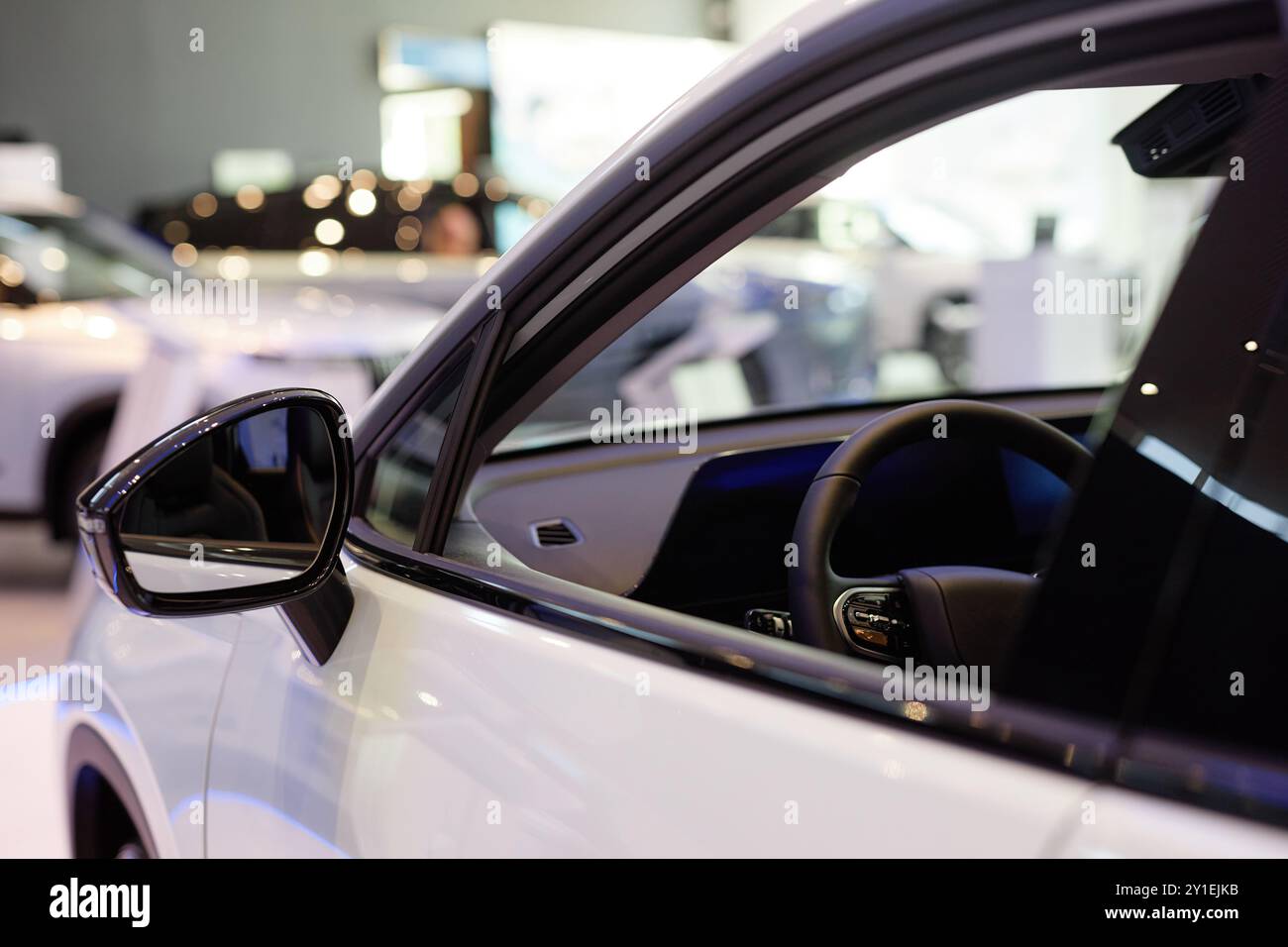 Side view mirror of shiny white car with opened window displayed in ...