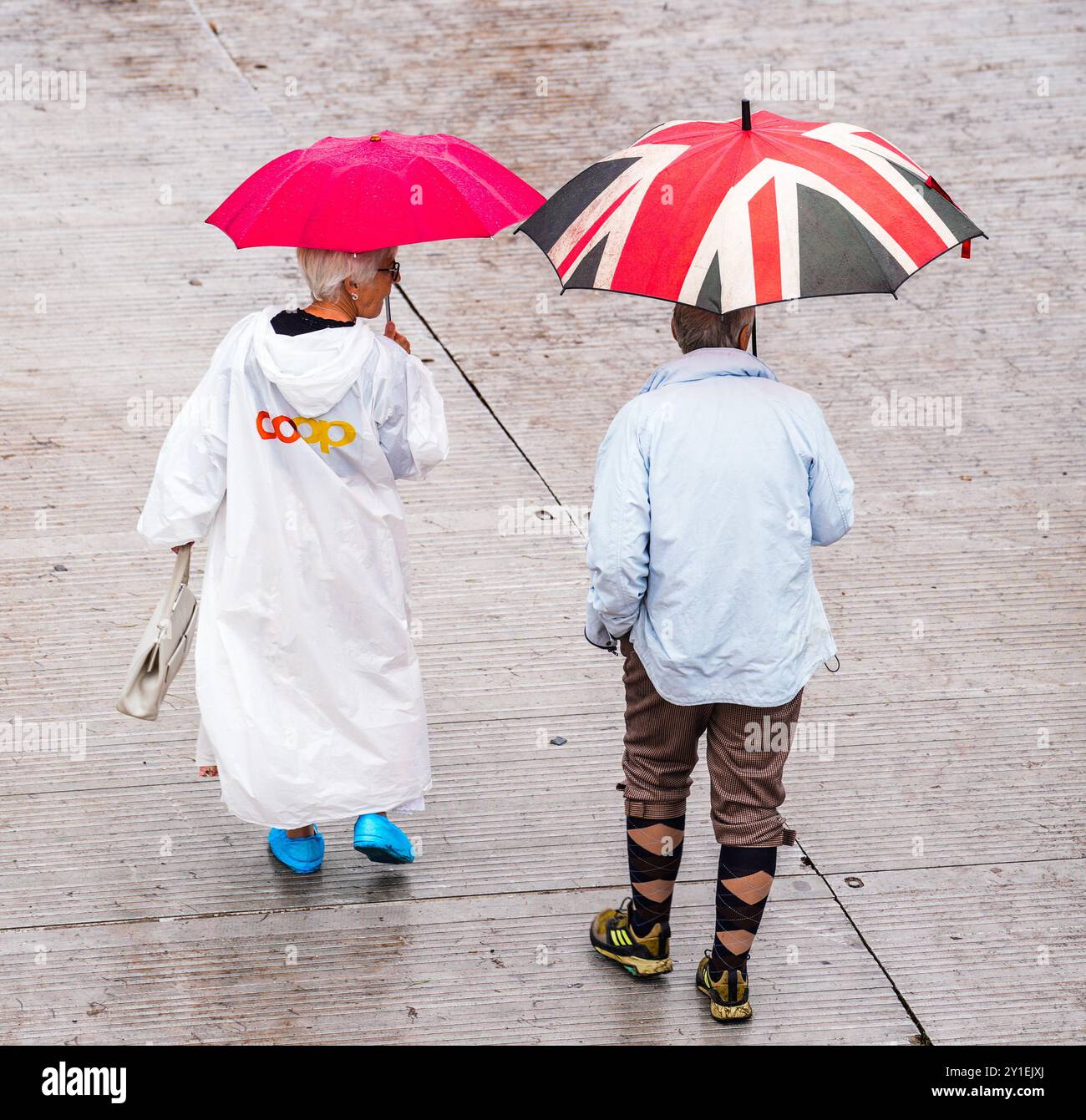 Goodwood Revival. Looking down on a couple in white raincoats and pink ...