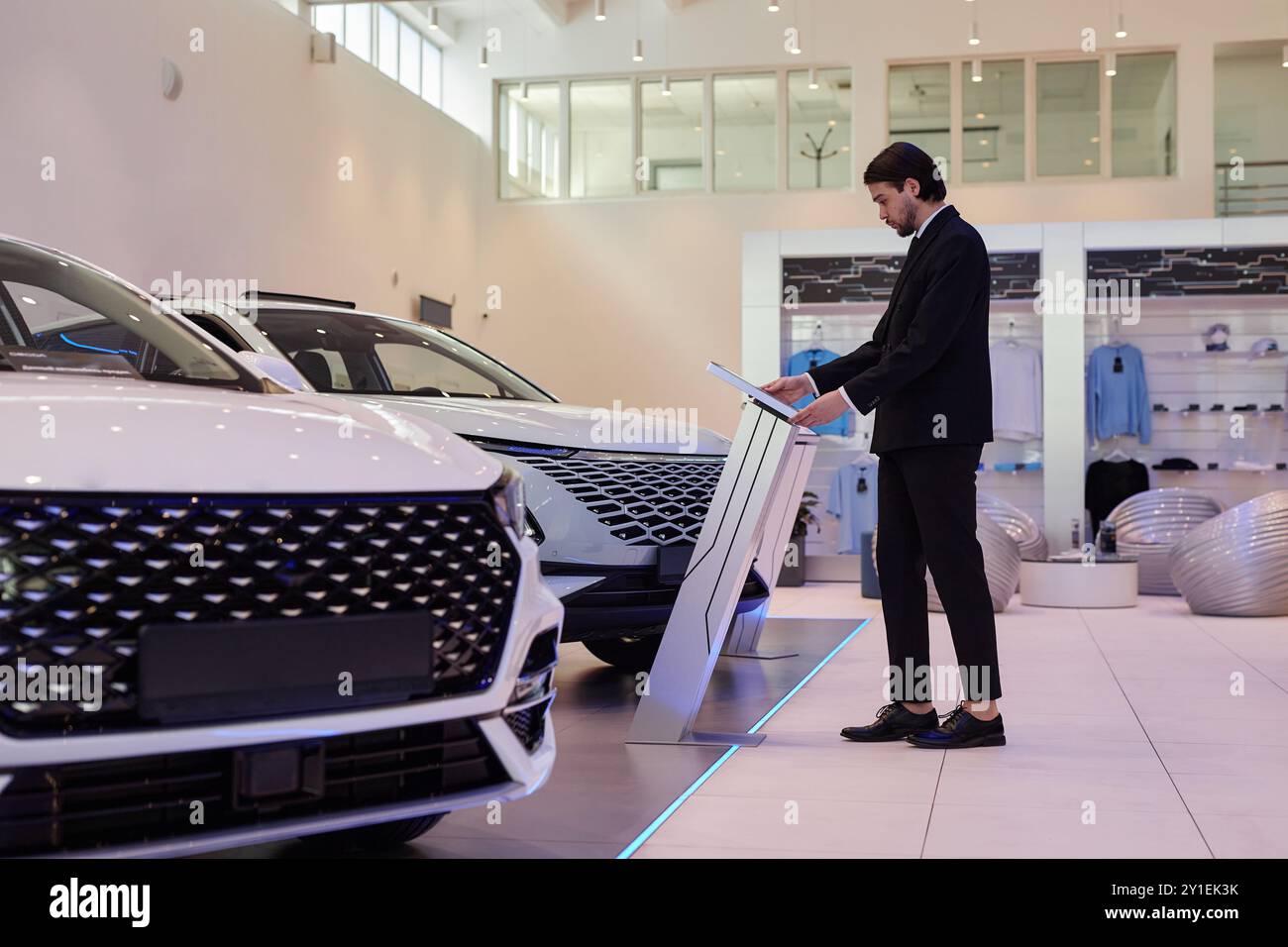Side view of Central Asian male auto dealer in formal black suit ...