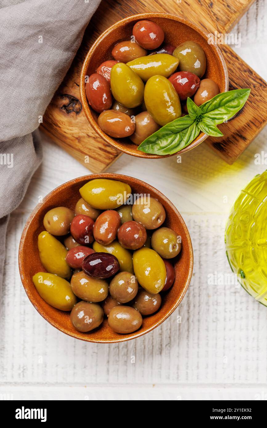 An assortment of various olives presented in a bowl and olive oil ...