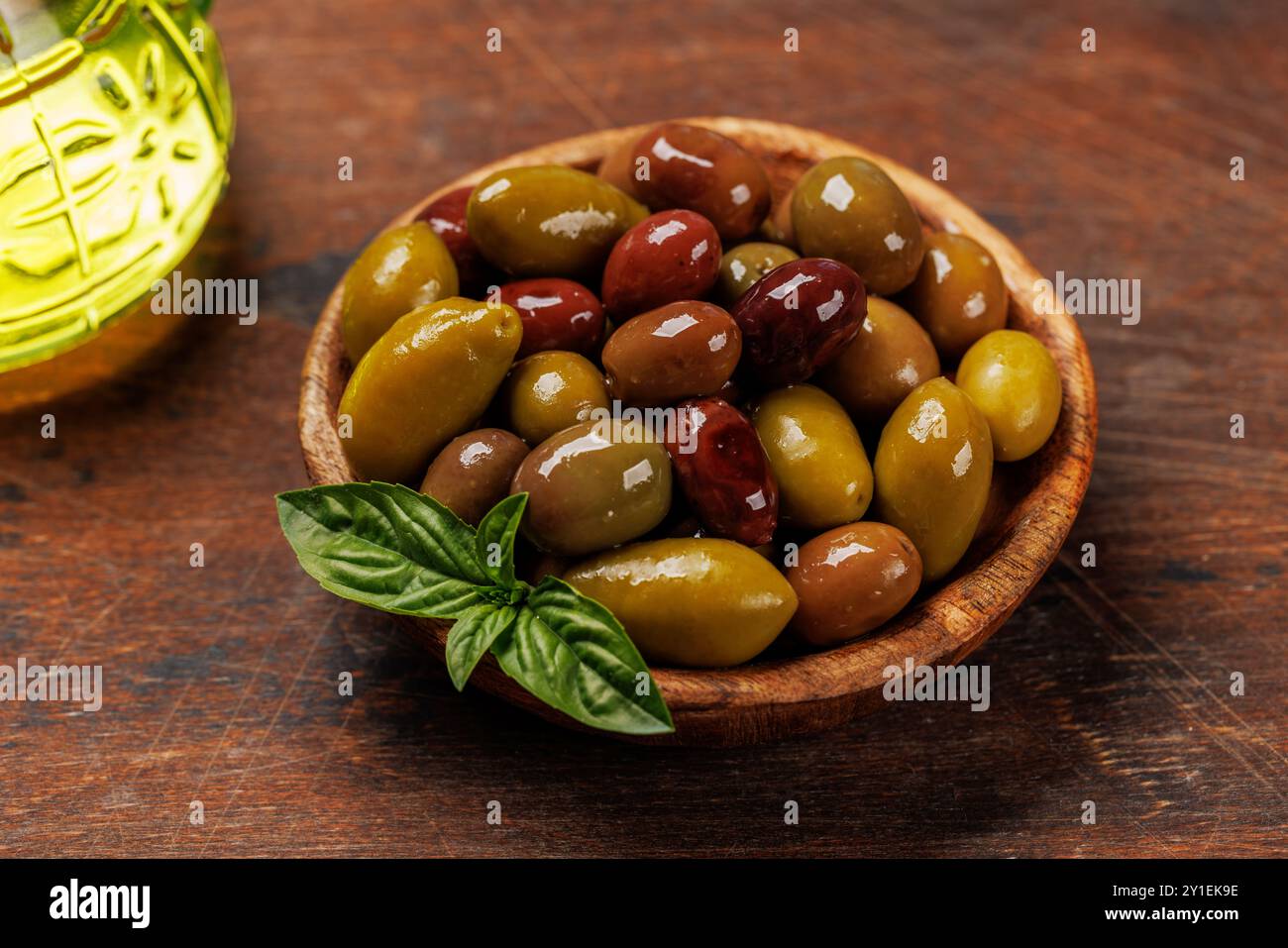 An assortment of various olives presented in a bowl and olive oil ...