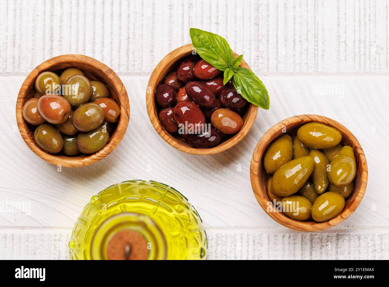 An assortment of various olives presented in a bowl and olive oil ...