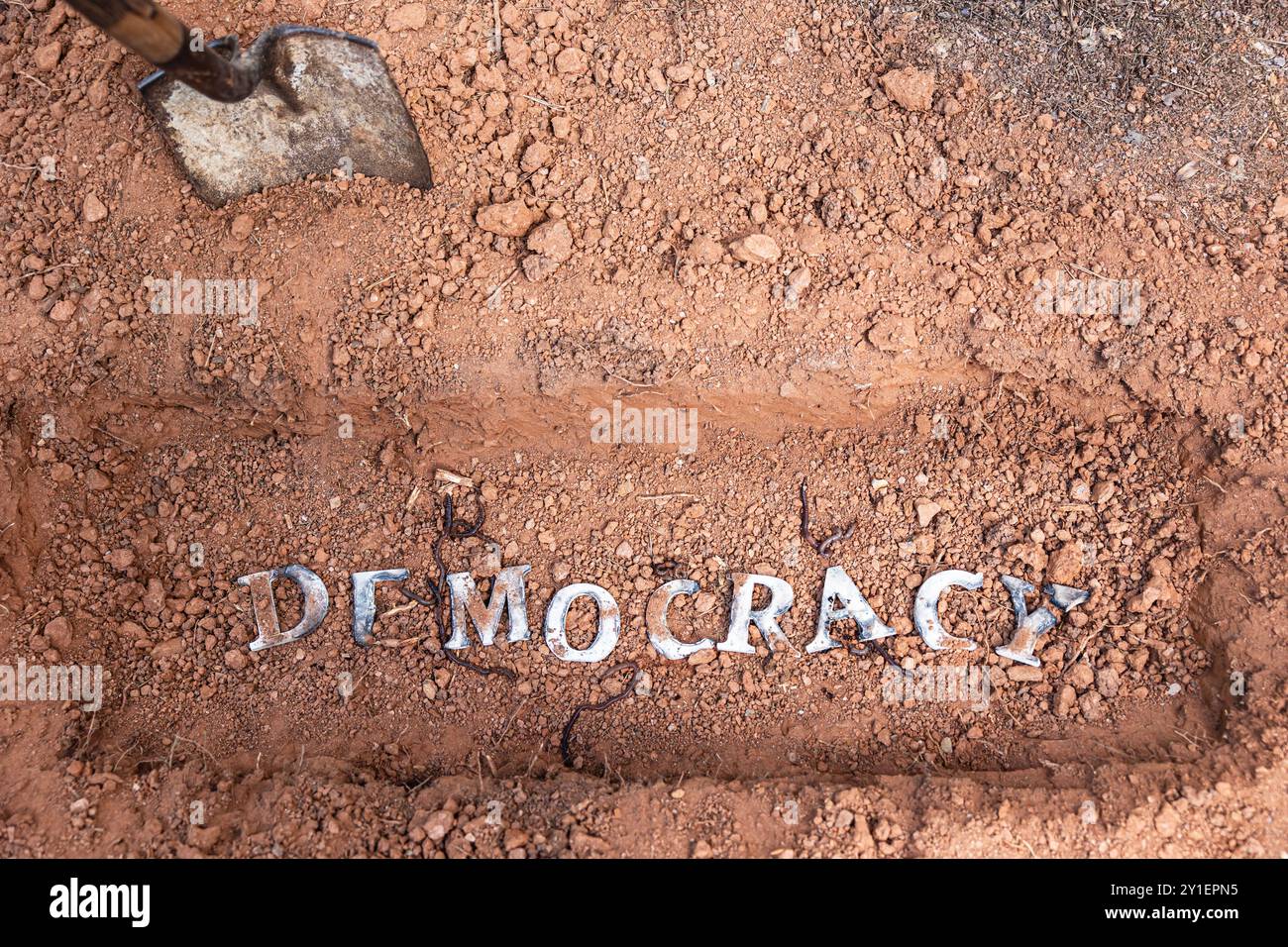 Wood letters that spell out the word democracy, lie in a shallow grave ...