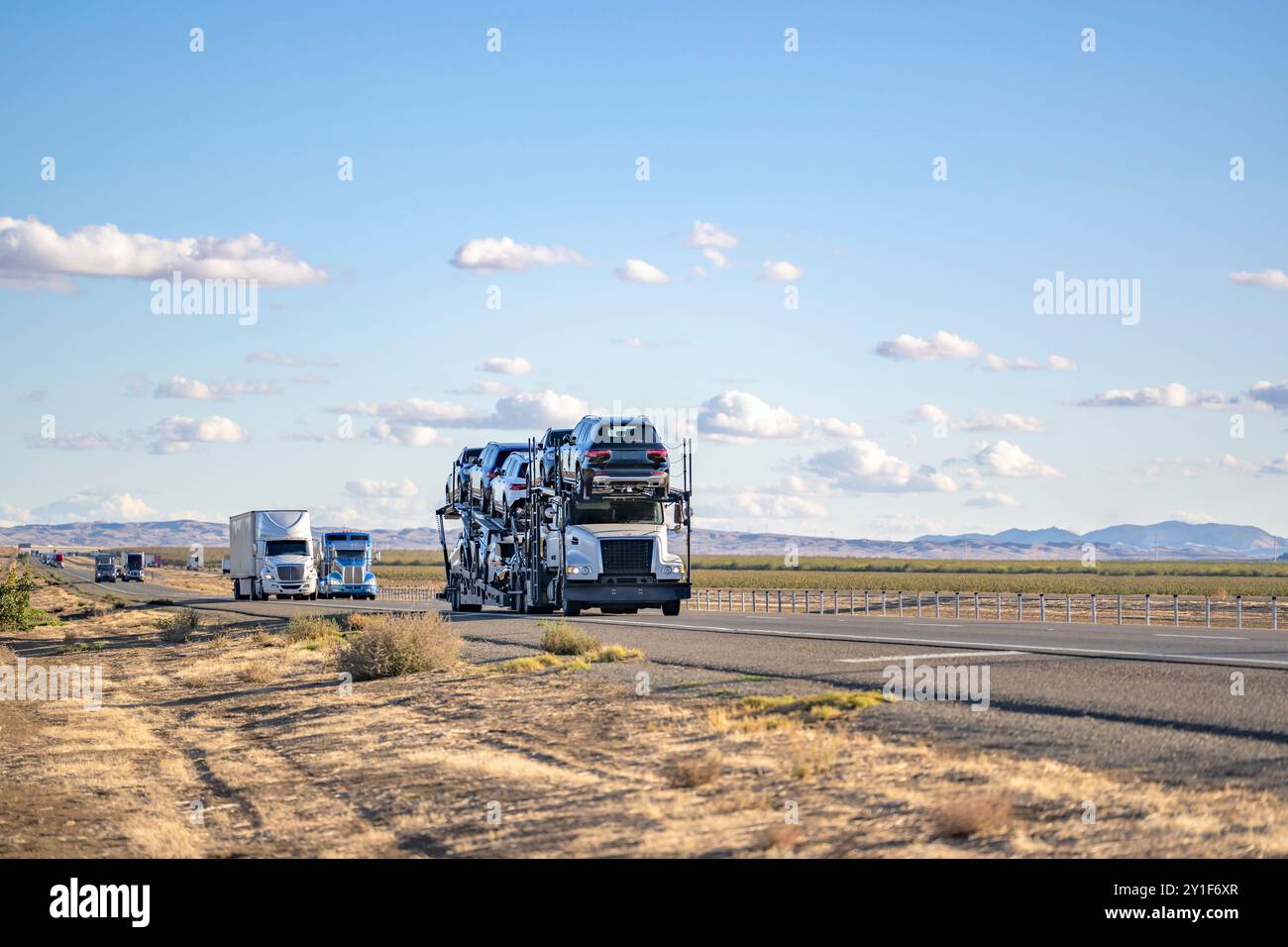 White car hauler big rig semi truck transporting cars on two level semi ...