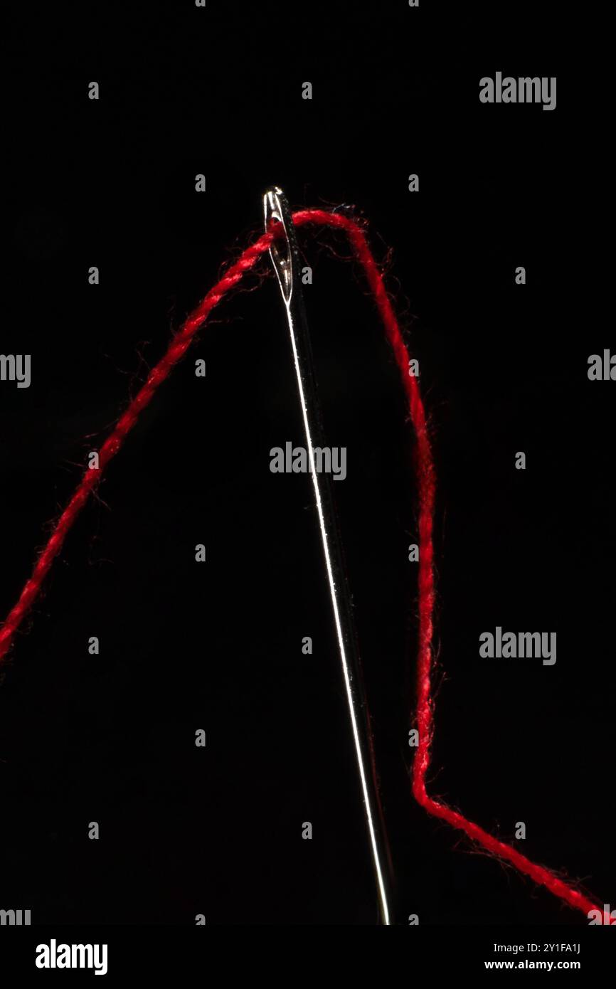 Macro of a red thread through the eye of a needle Stock Photo - Alamy