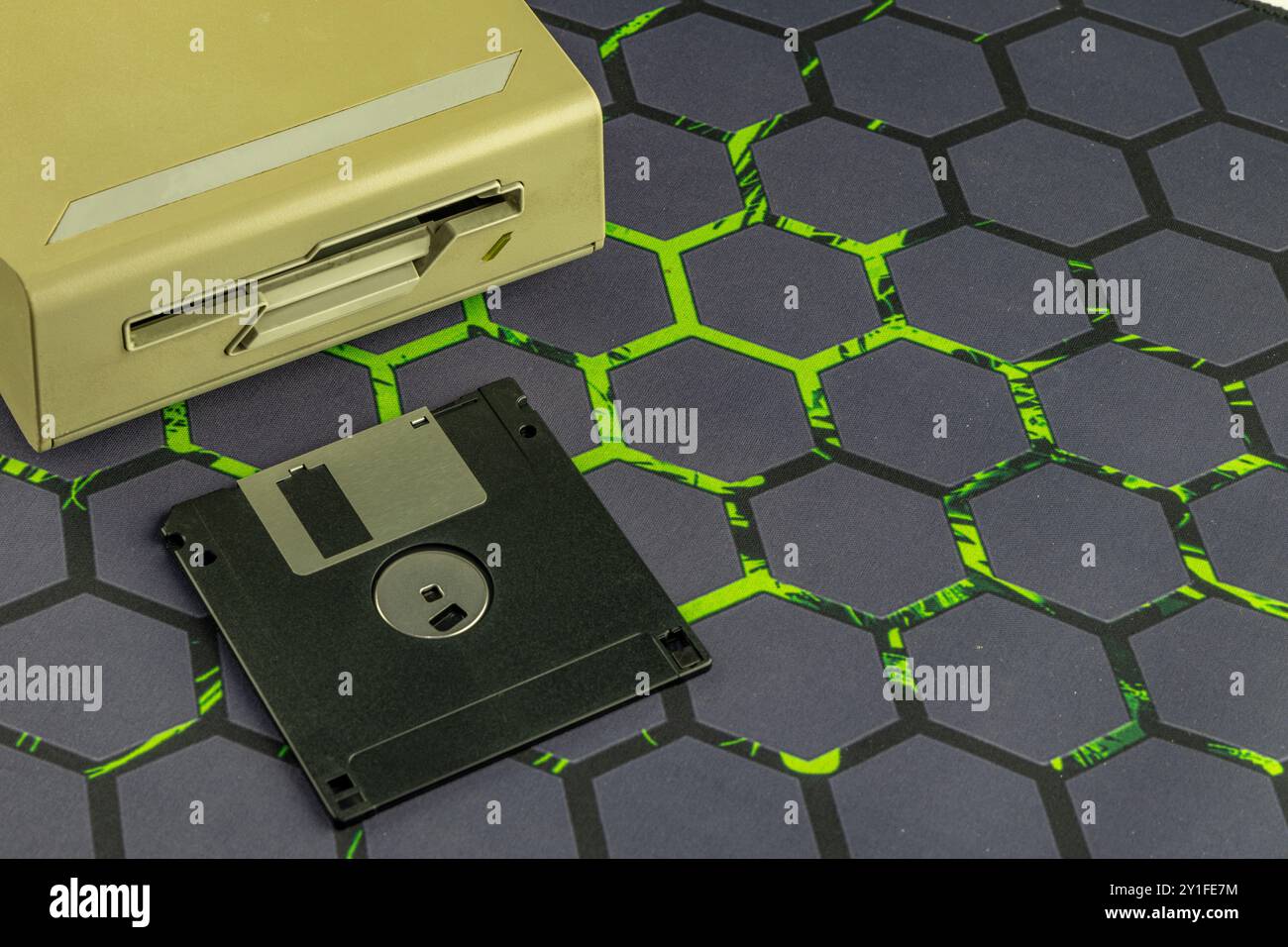 Old damaged 3.5 inch floppy disk drive, colorful floppy disks arranged on a mouse and keyboard ...