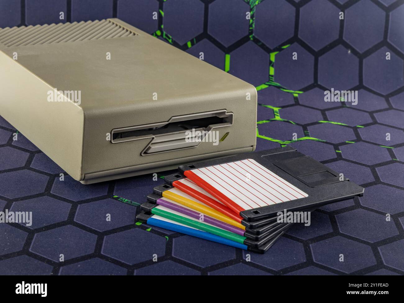 Old damaged 3.5 inch floppy disk drive, colorful floppy disks arranged on a mouse and keyboard ...