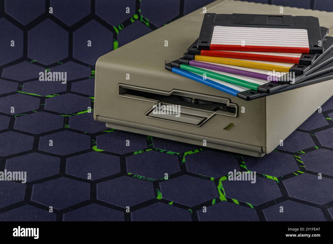Old damaged 3.5 inch floppy disk drive, colorful floppy disks arranged on a mouse and keyboard ...