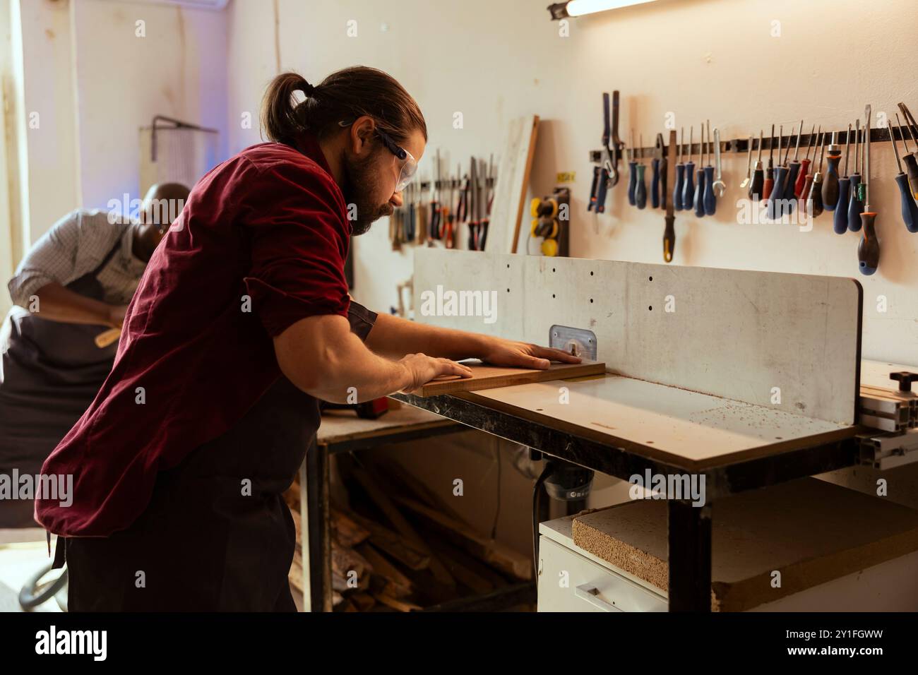 Woodworking expert wears protection gear while inserting plank in ...
