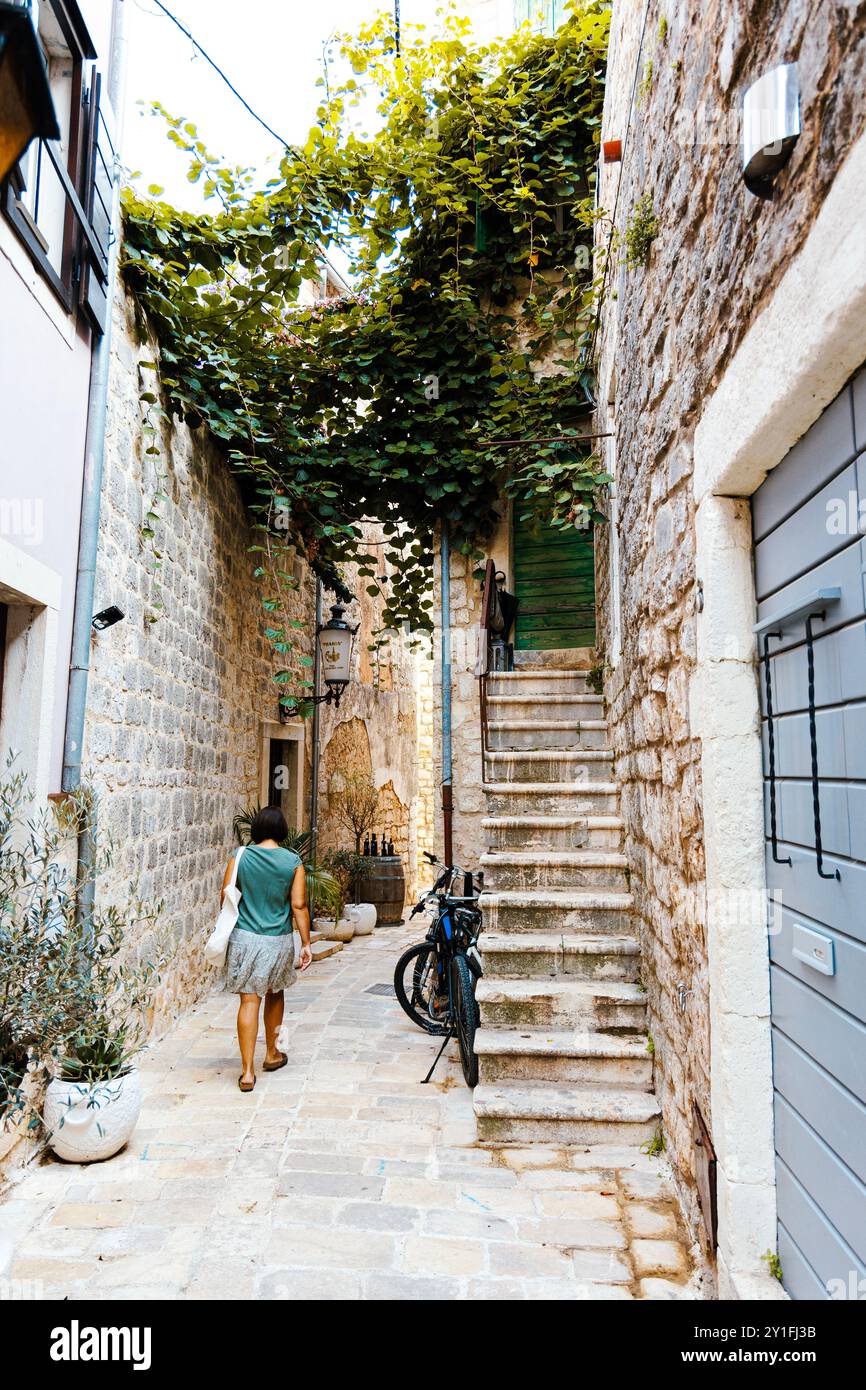 Woman walking down narrow street in the village of Stari Grad, Hvar ...
