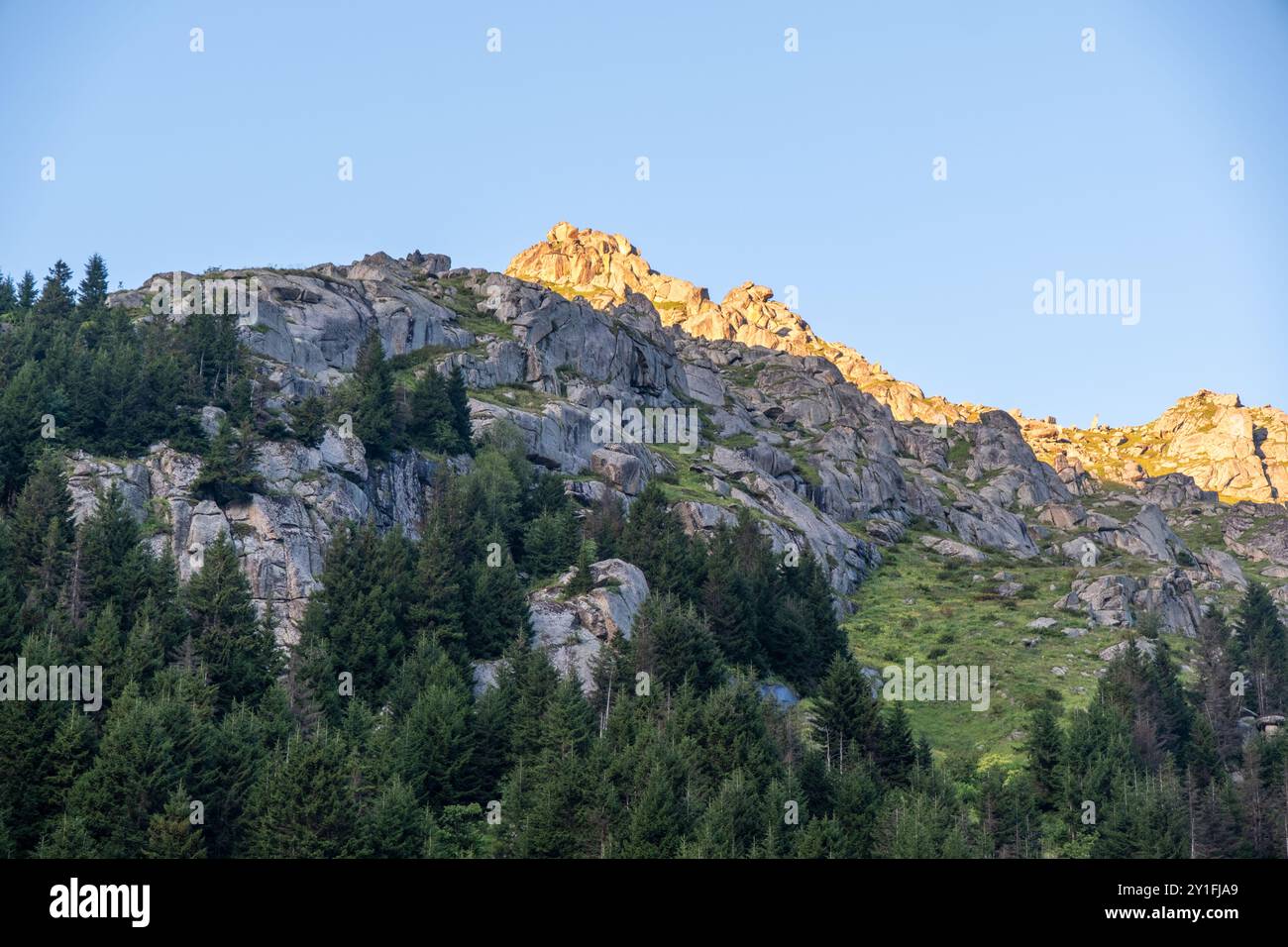 The sunlit slopes of Amaklit Plateau in Camlihemsin, with rugged rocks and lush greenery, offer ...