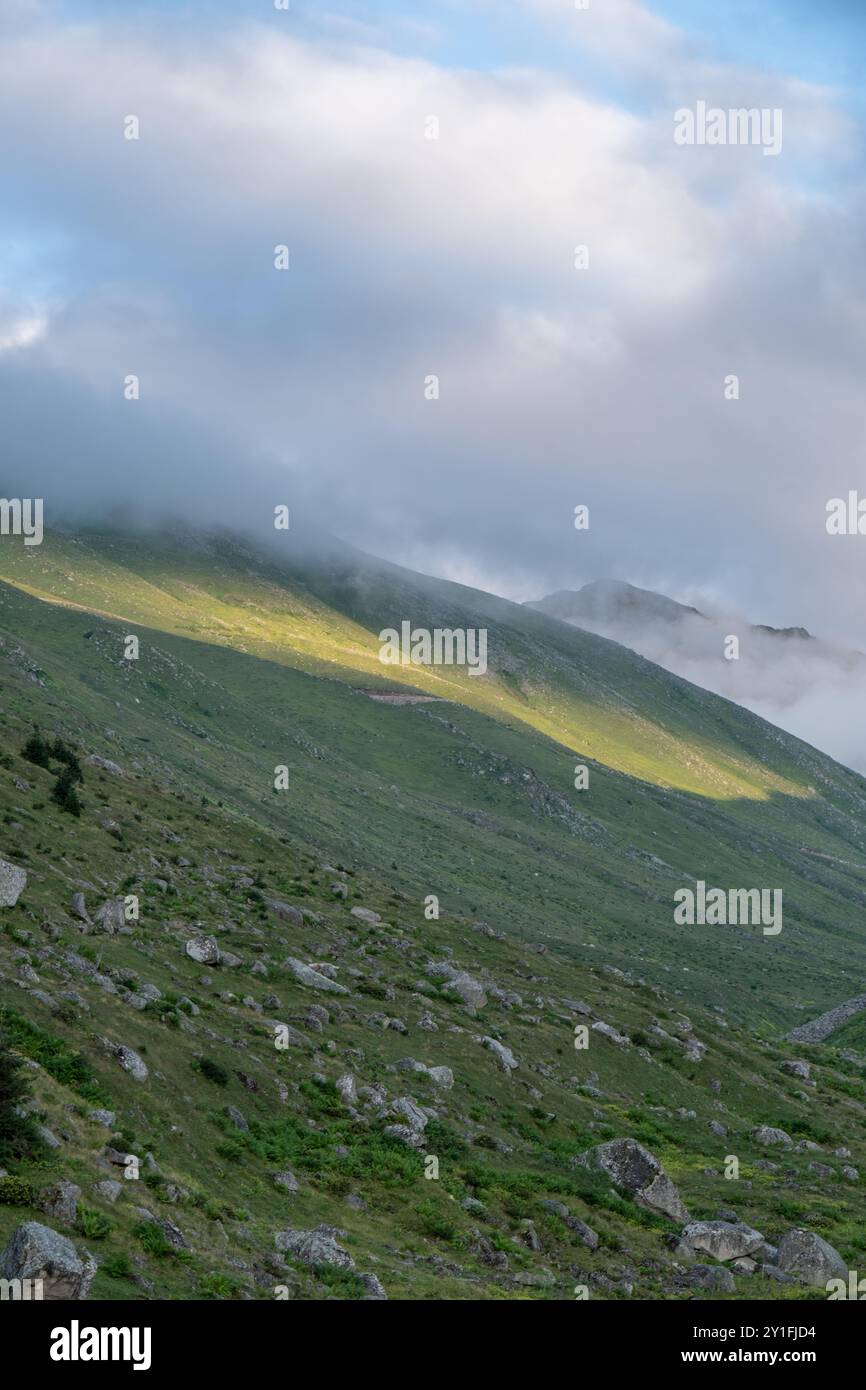 The sunlit slopes of Amaklit Plateau in Camlihemsin, with rugged rocks and lush greenery, offer ...