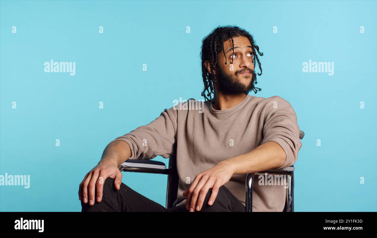 Bored Middle Eastern man with disability in wheelchair impatiently ...