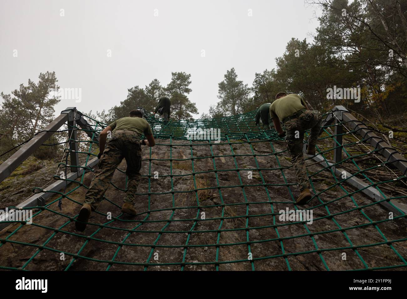 U.S. Marines climb up a rope net during an obstacle course at Berga ...