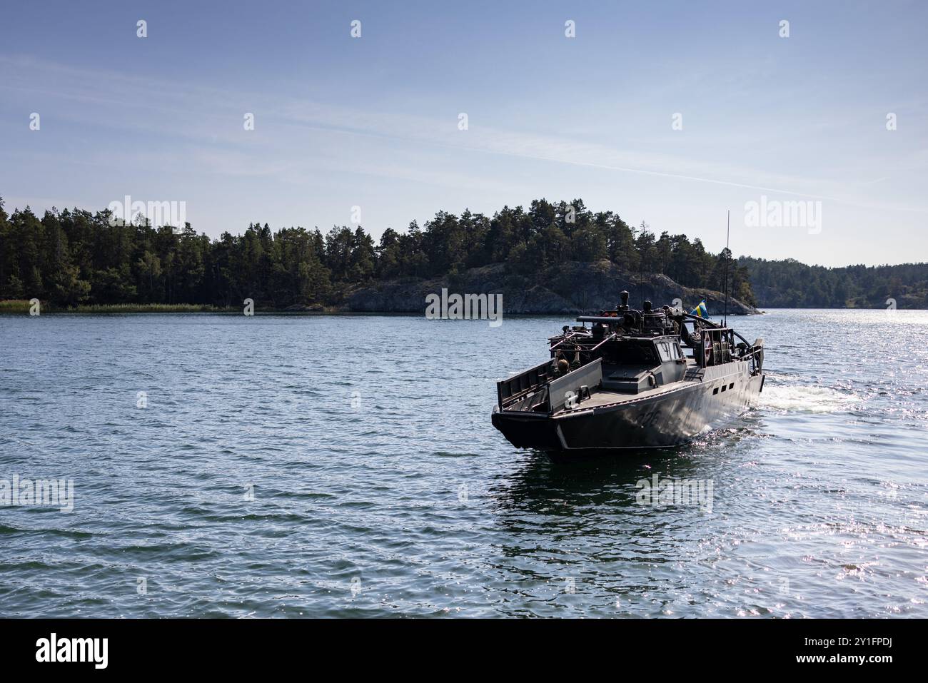 Swedish service members bring a CB90 combat boat to shore during a CB90 ...