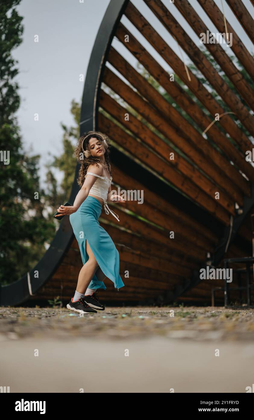 Young girl performing modern dance movements in green park with ...