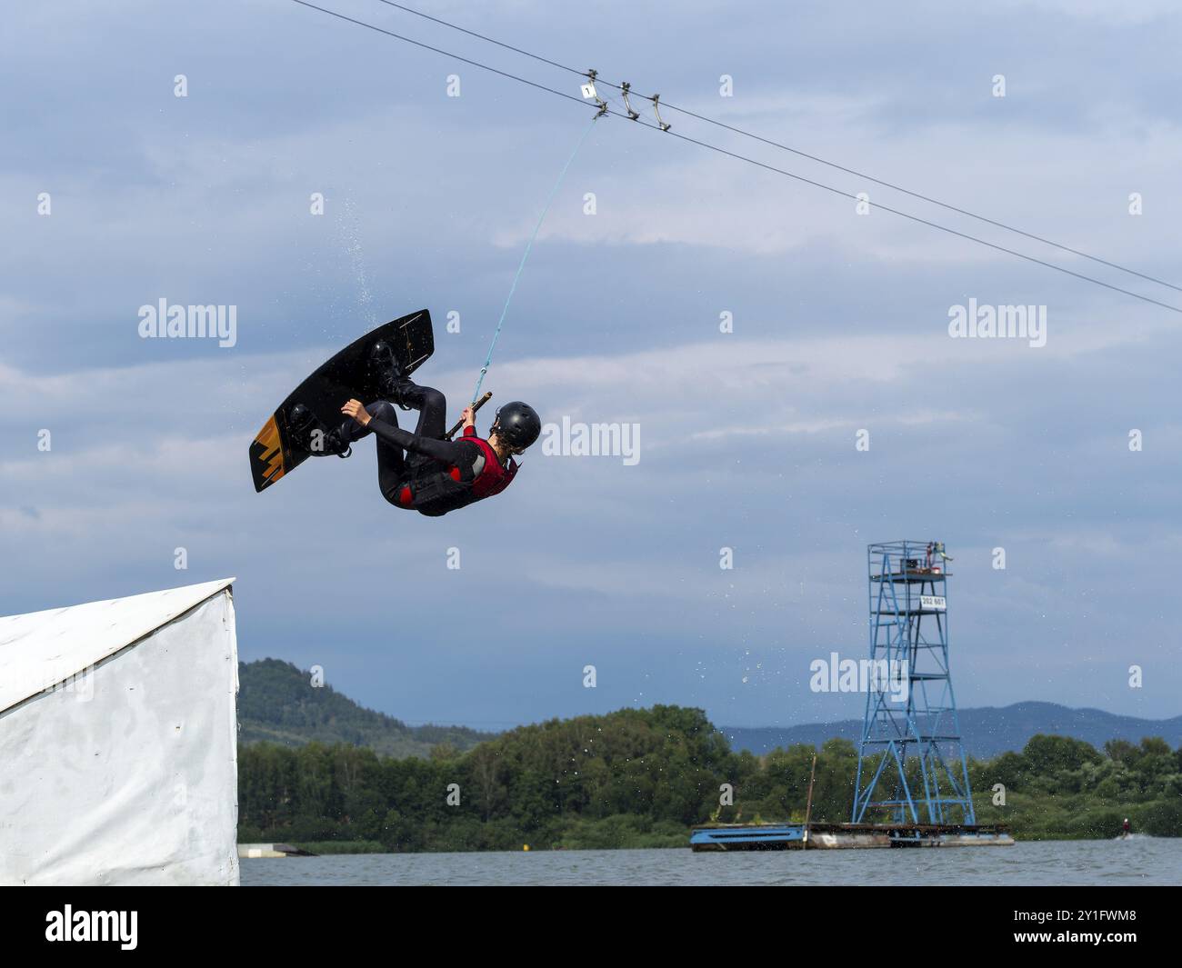 Man jumping with wakeboard over obstacle, somersault, water sports ...