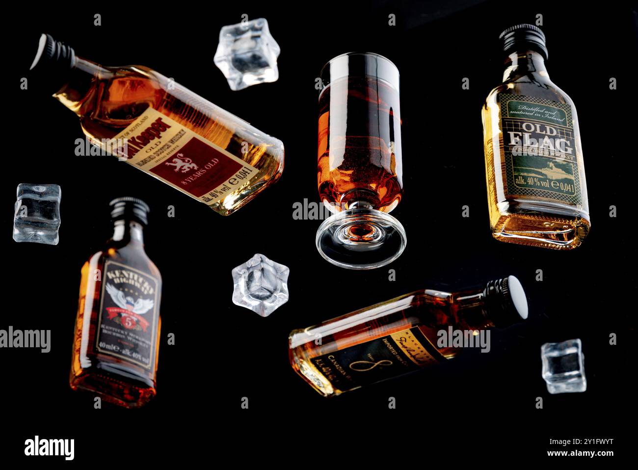 Four whisky bottles and a glass of whisky between floating ice cube ...