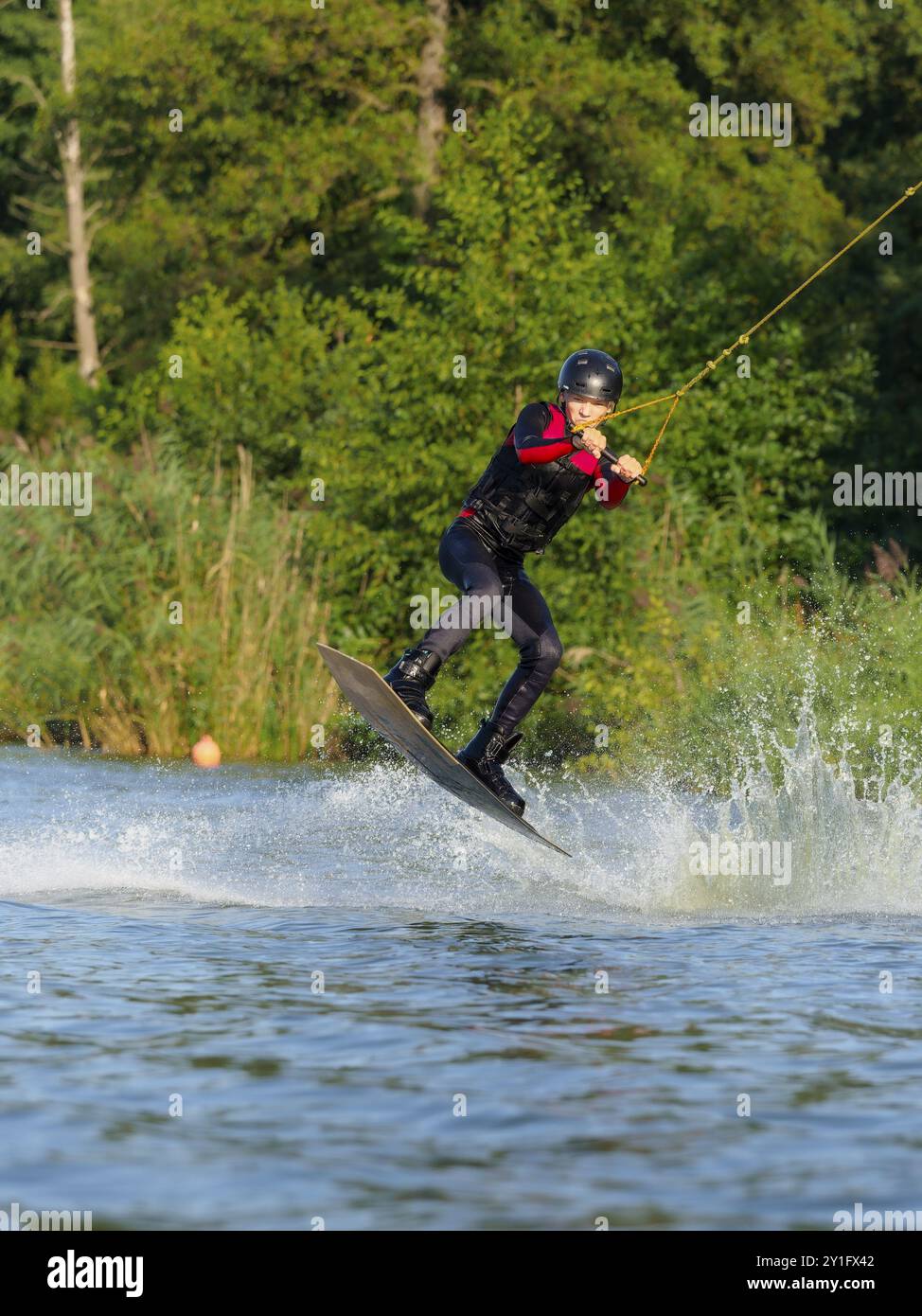 Young man jumping with wakeboard in lake, water sports, water skiing in ...