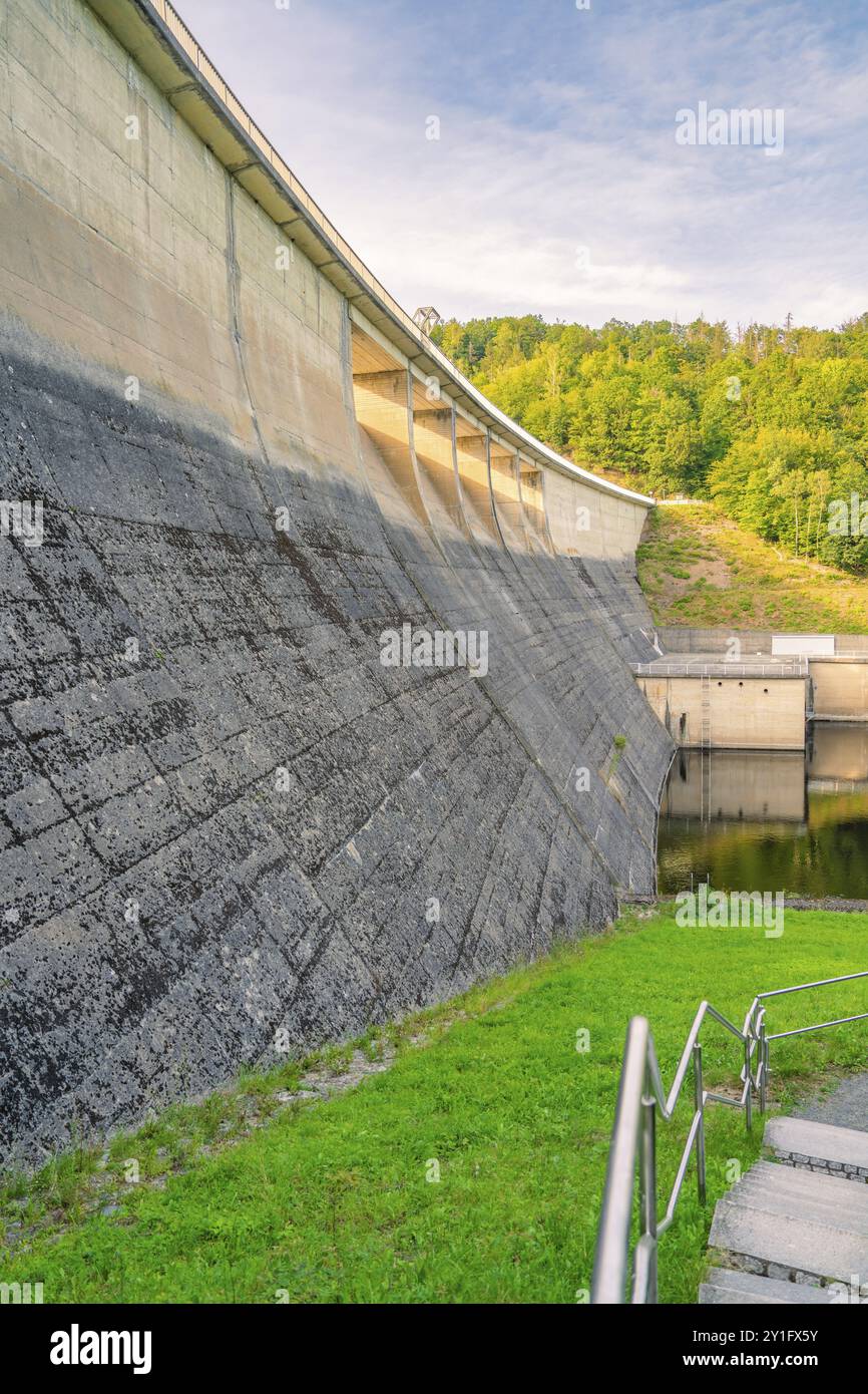Concrete dam surrounded by green grass and lush forest in the ...