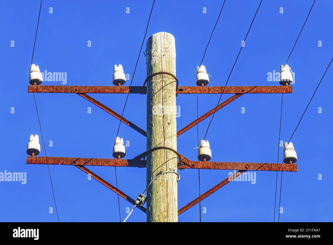 Old telephone pole with white porcelain insulators against a blue sky ...