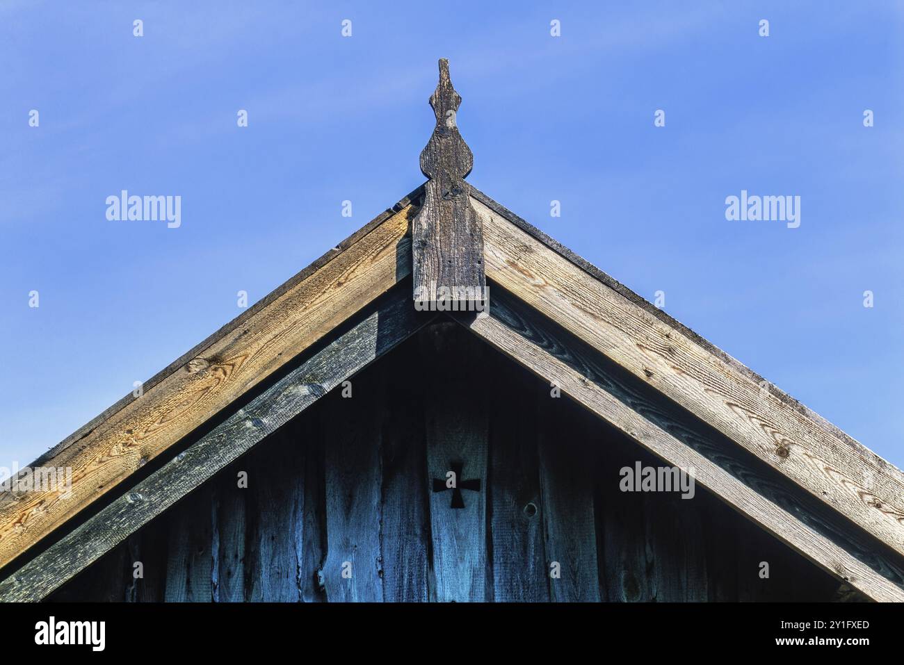 Roof ridge on an old wooden house with joinery and a cross on the gable ...