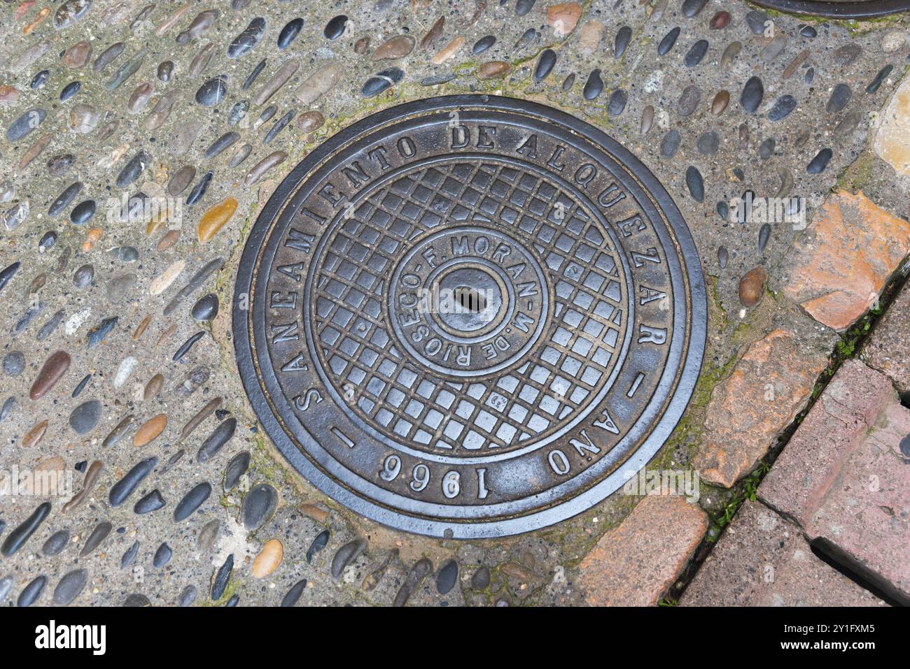 Manhole cover installed in Alquezar in 1966, surrounded by uneven ...